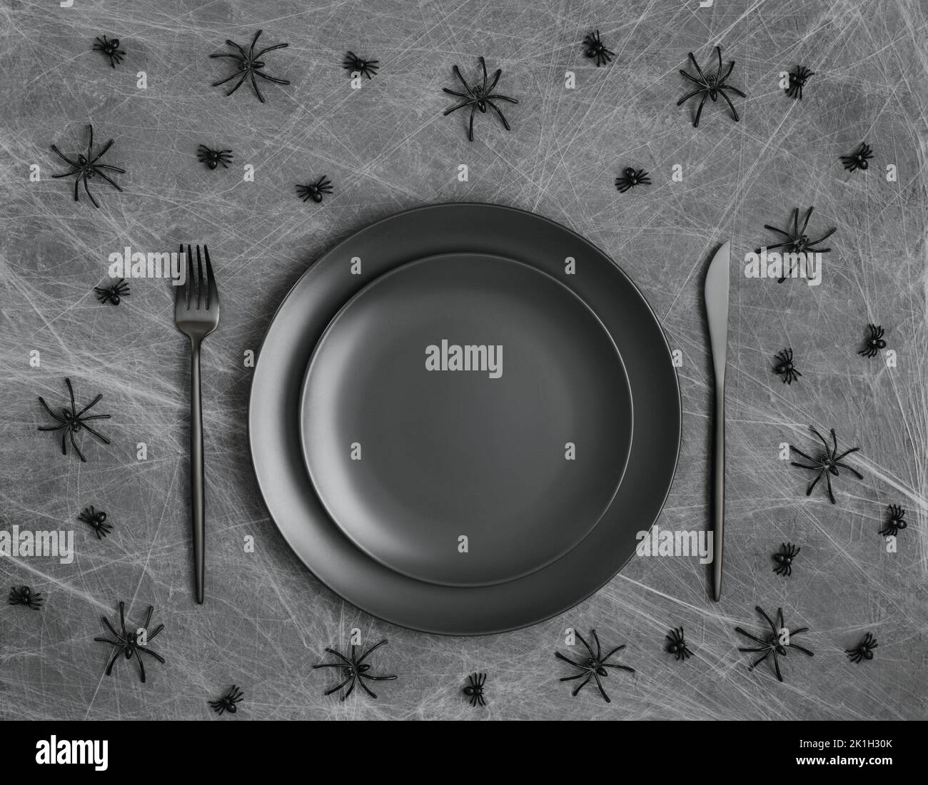 Halloween table setting with black crockery and spiders in the web ...