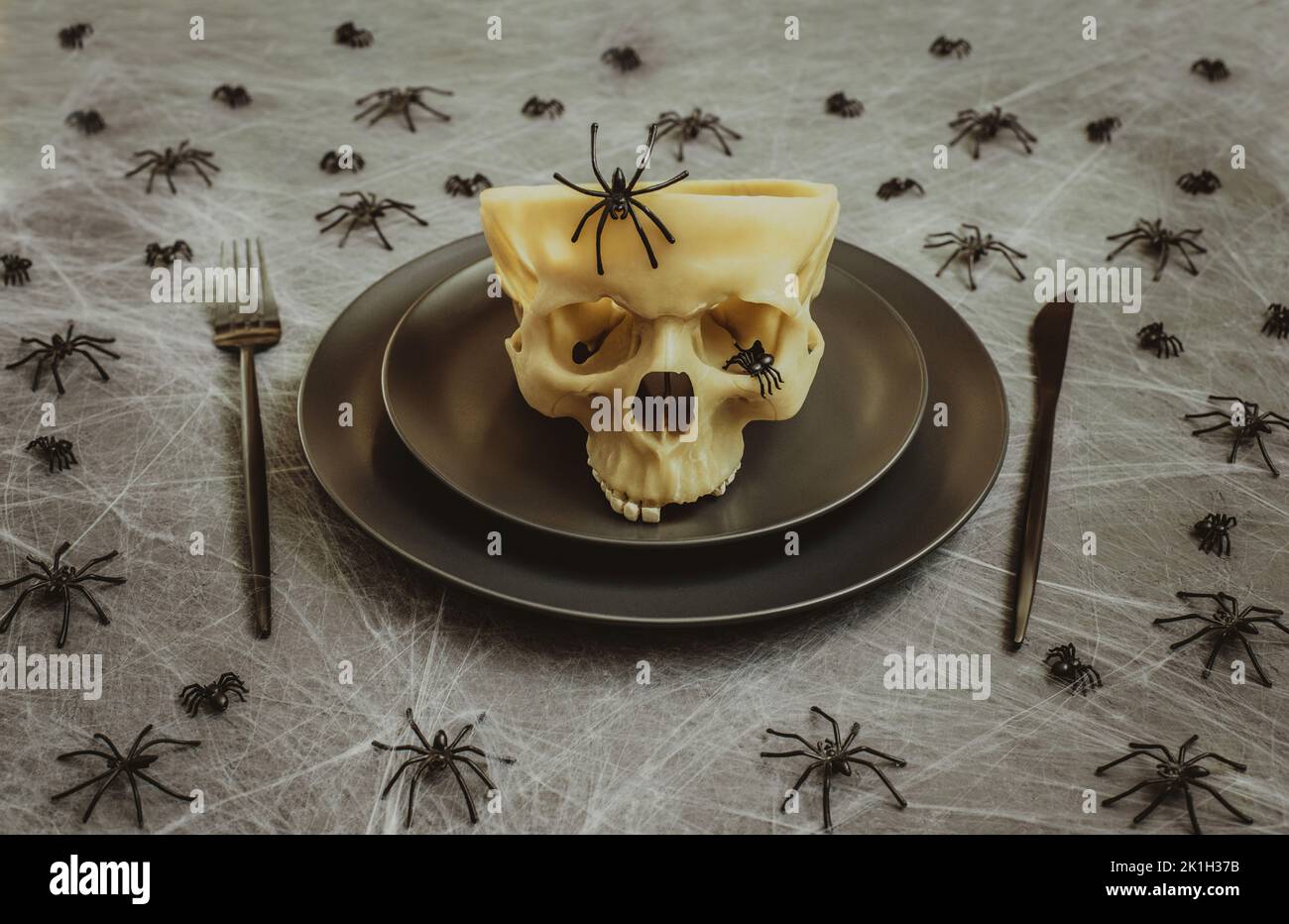 Halloween table setting with black cutlery, skull and spiders in a web ...