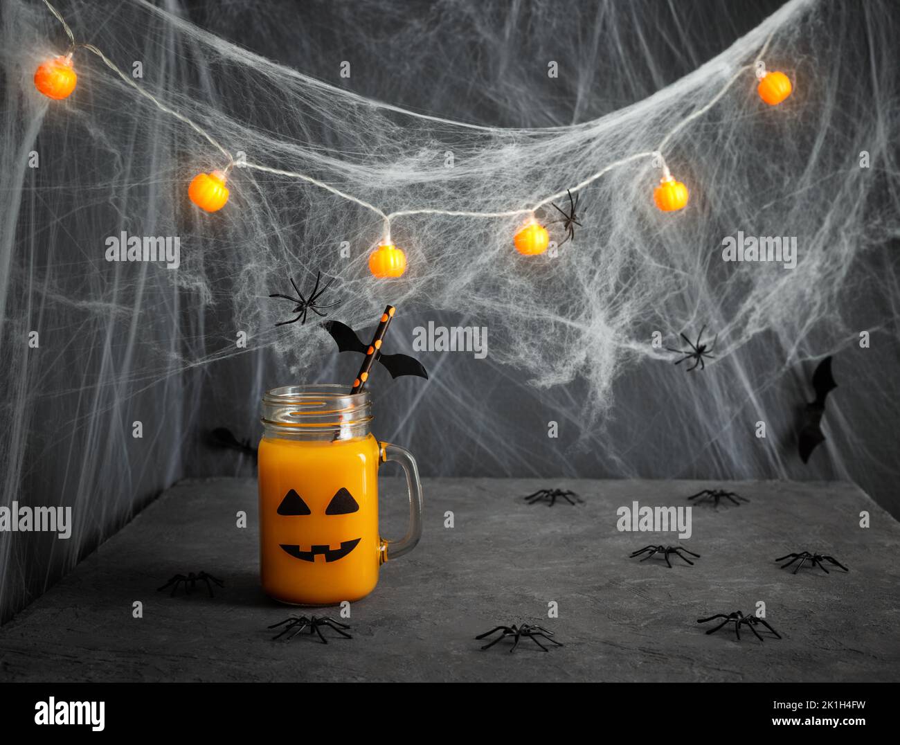 Halloween pumpkin juice in a glass jar with a scary face, spiders and ...