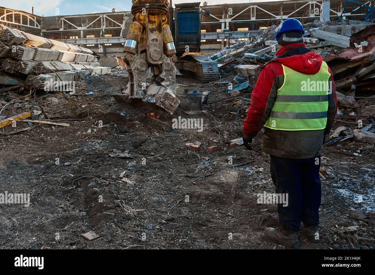 Excavator destroyer removes debris under worker control Stock Photo - Alamy