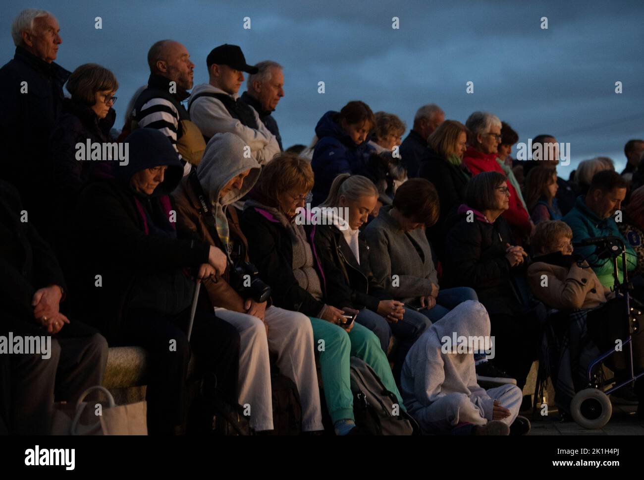 People observe a one minute silence at a service of reflection to ...