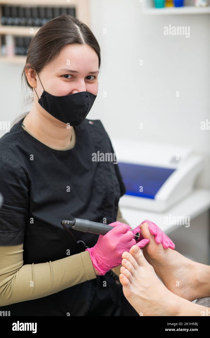 The pedicure master processes the client's foot using an apparatus with ...