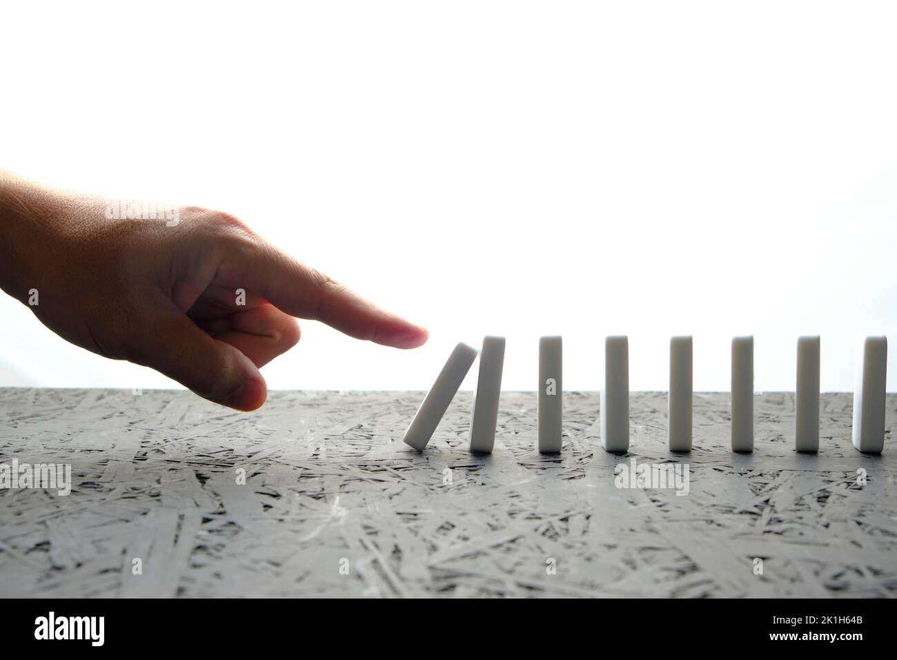 Hand pushing with a finger dominoes standing white background Stock ...
