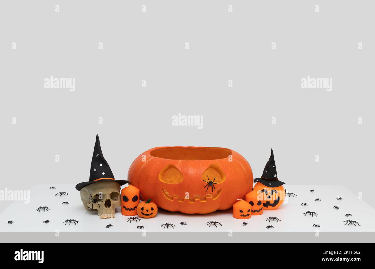 Halloween composition with pumpkin, skull, and candles on a white ...