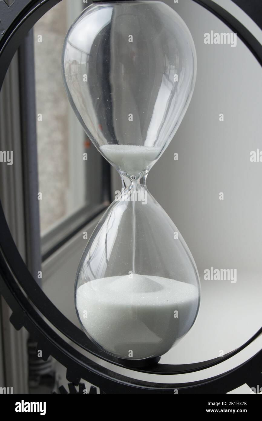 Close up of an hourglass with sand flowing from the upper part ...