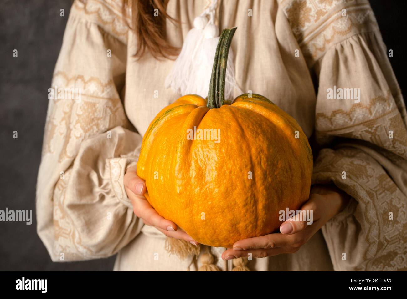 A girl in a Ukrainian dress holds a pumpkin, a symbol of rejection of a ...