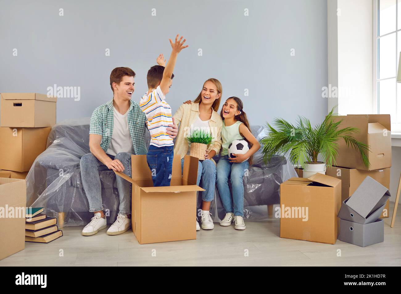 Cheerful funny family playing and having fun in their new house full of ...