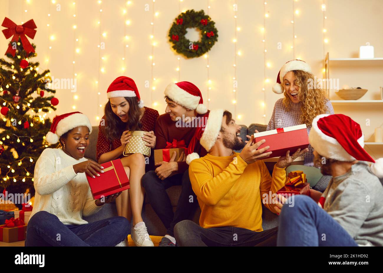 Group of cheerful friends exchange gifts and have fun during Christmas ...