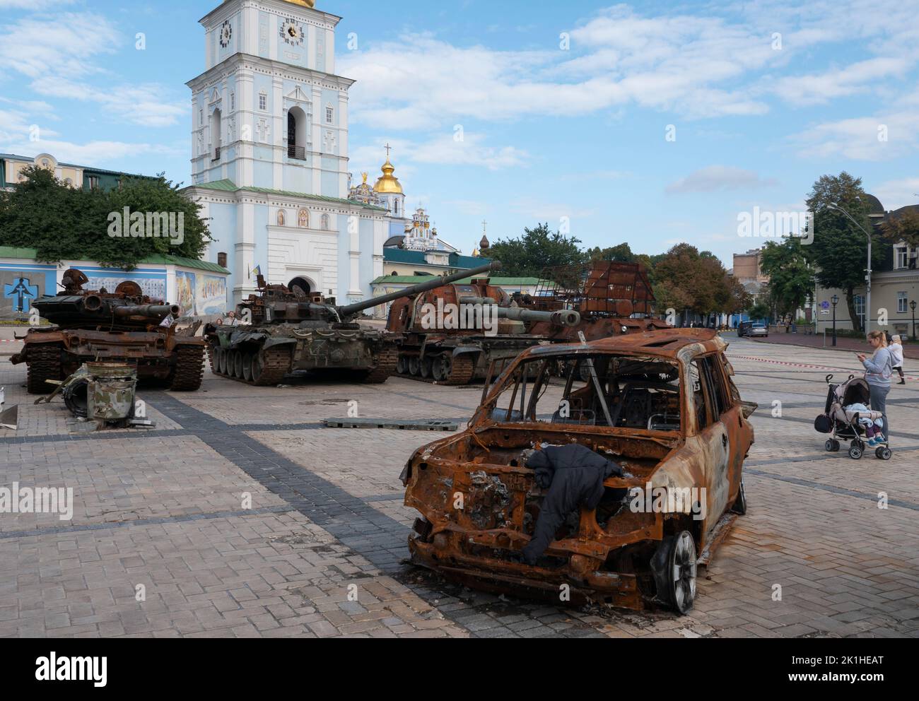 People walk around destroyed vehicles at Mykhailivska Square in Kyiv ...