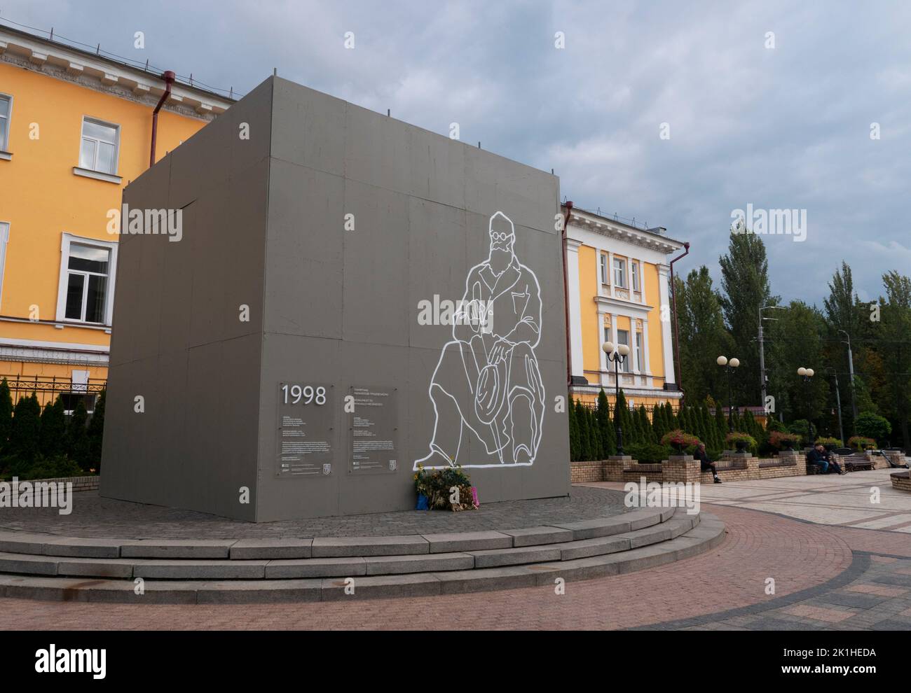 People sit near the protected monument to Mykhailo Hrushevsky in Kyiv ...