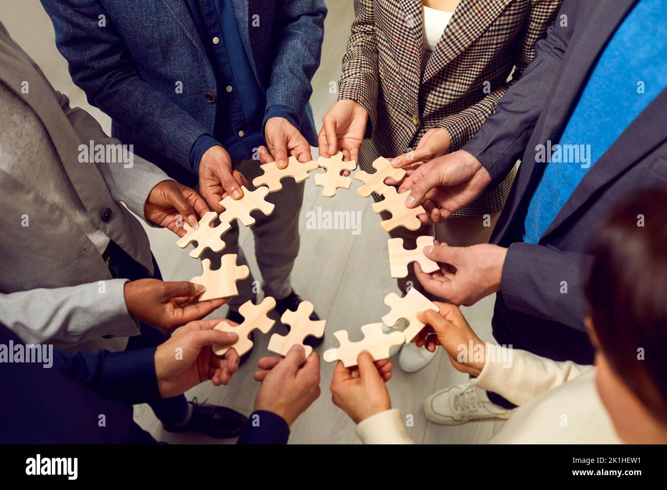 Diverse team of business people cooperate and make a circle from jigsaw ...