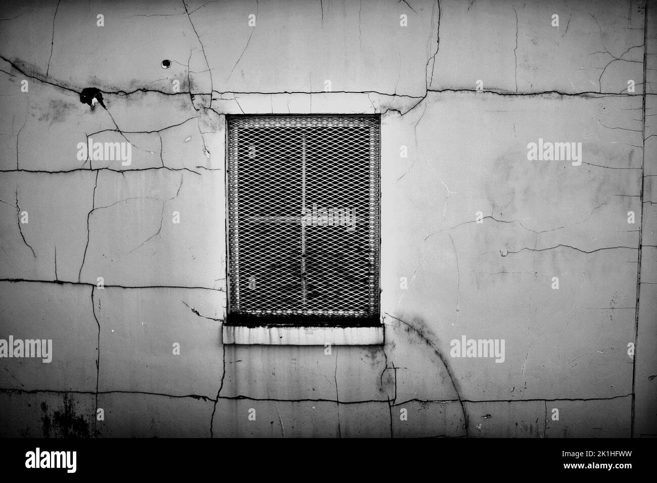 A closed screen window of an old house with cracks on the wall Stock ...