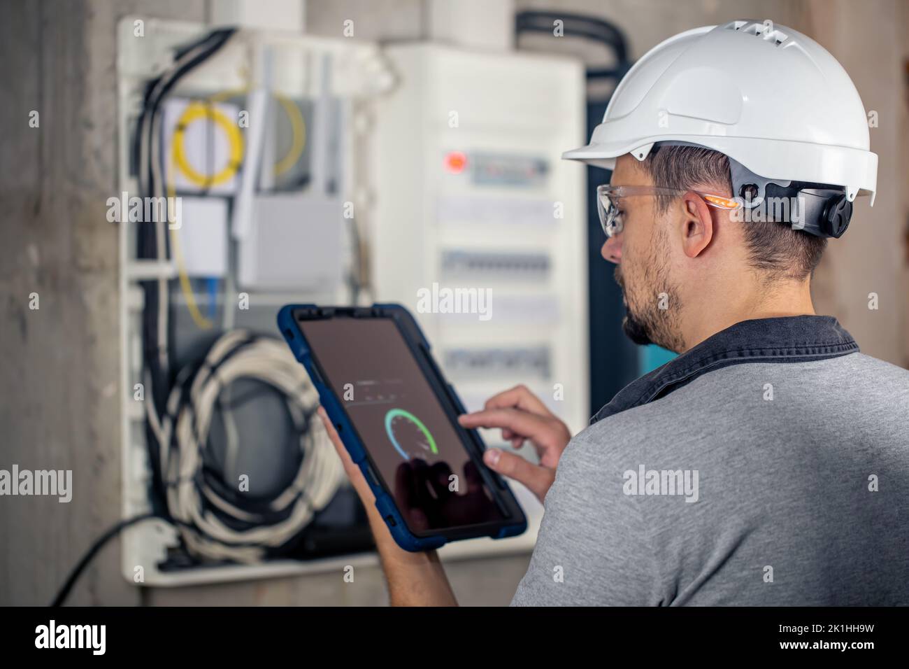 Man, an electrical technician working in a switchboard with fuses, uses a tablet Stock Photo - Alamy
