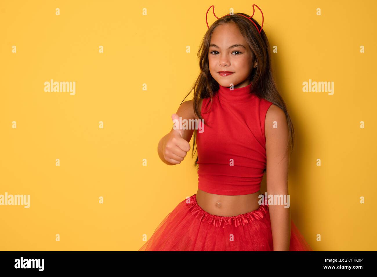 halloween, holiday and childhood concept - smiling brunette girl in red ...