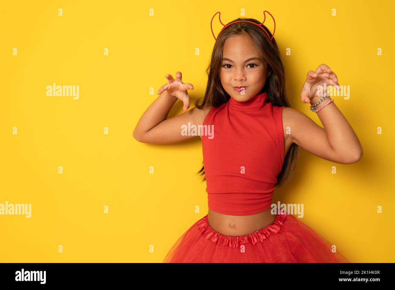 Portrait of an angry little girl in a costume, on a yellow background ...
