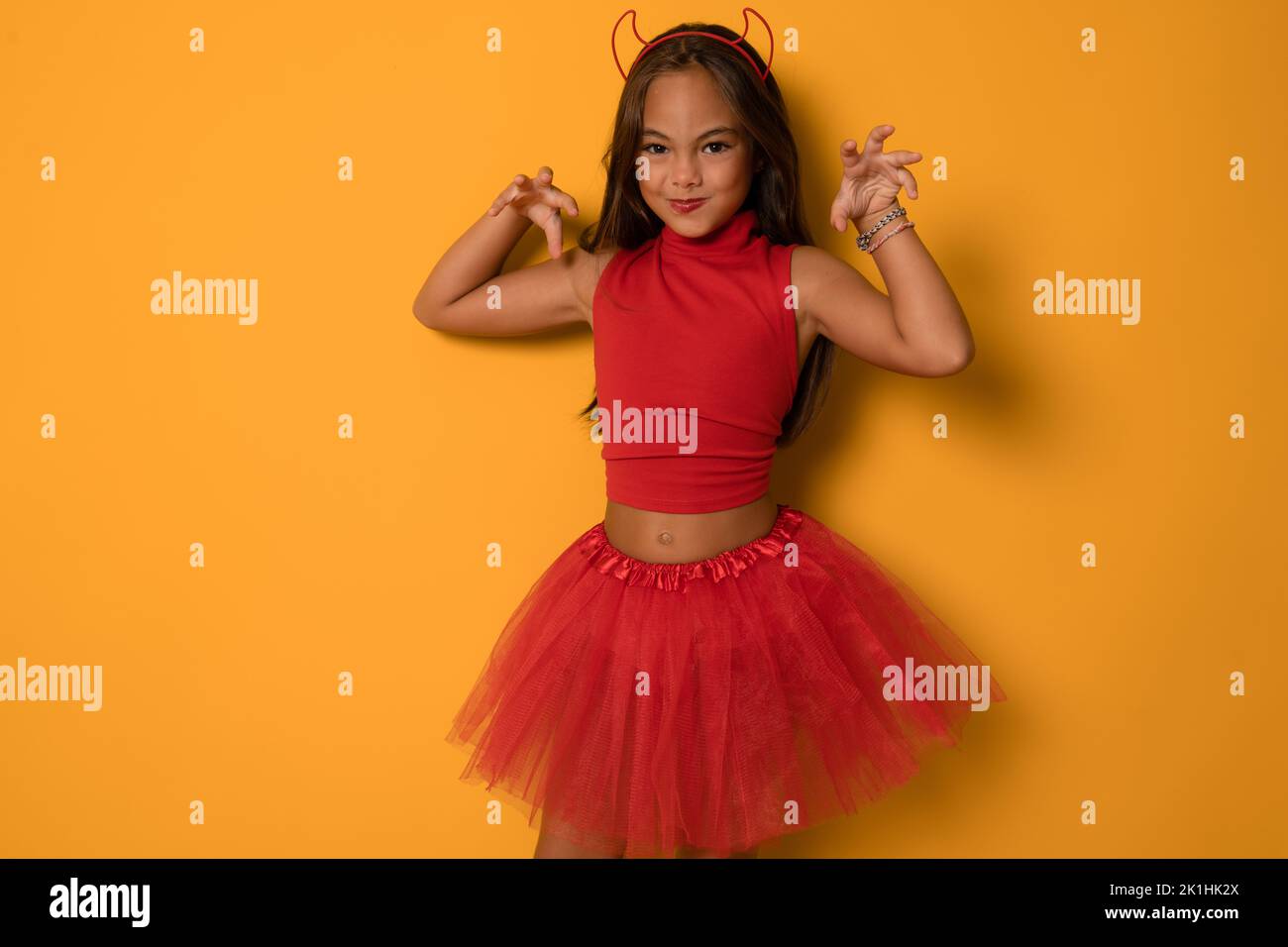 Portrait of an angry little girl in a costume, on a orange background ...
