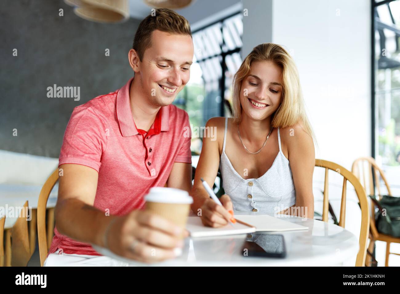 Happy students sitting in cafe table of university and doing homework ...