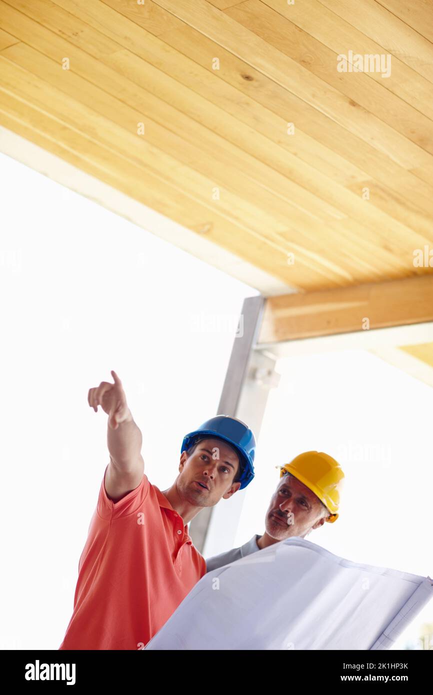 Making their plans a reality. Two men on a construction site assesssing ...