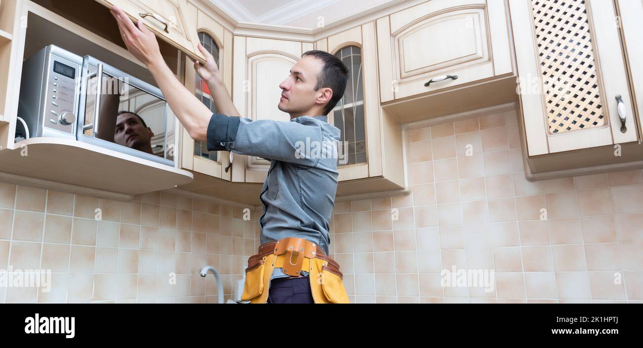kitchen installation. Worker assembling furniture Stock Photo - Alamy