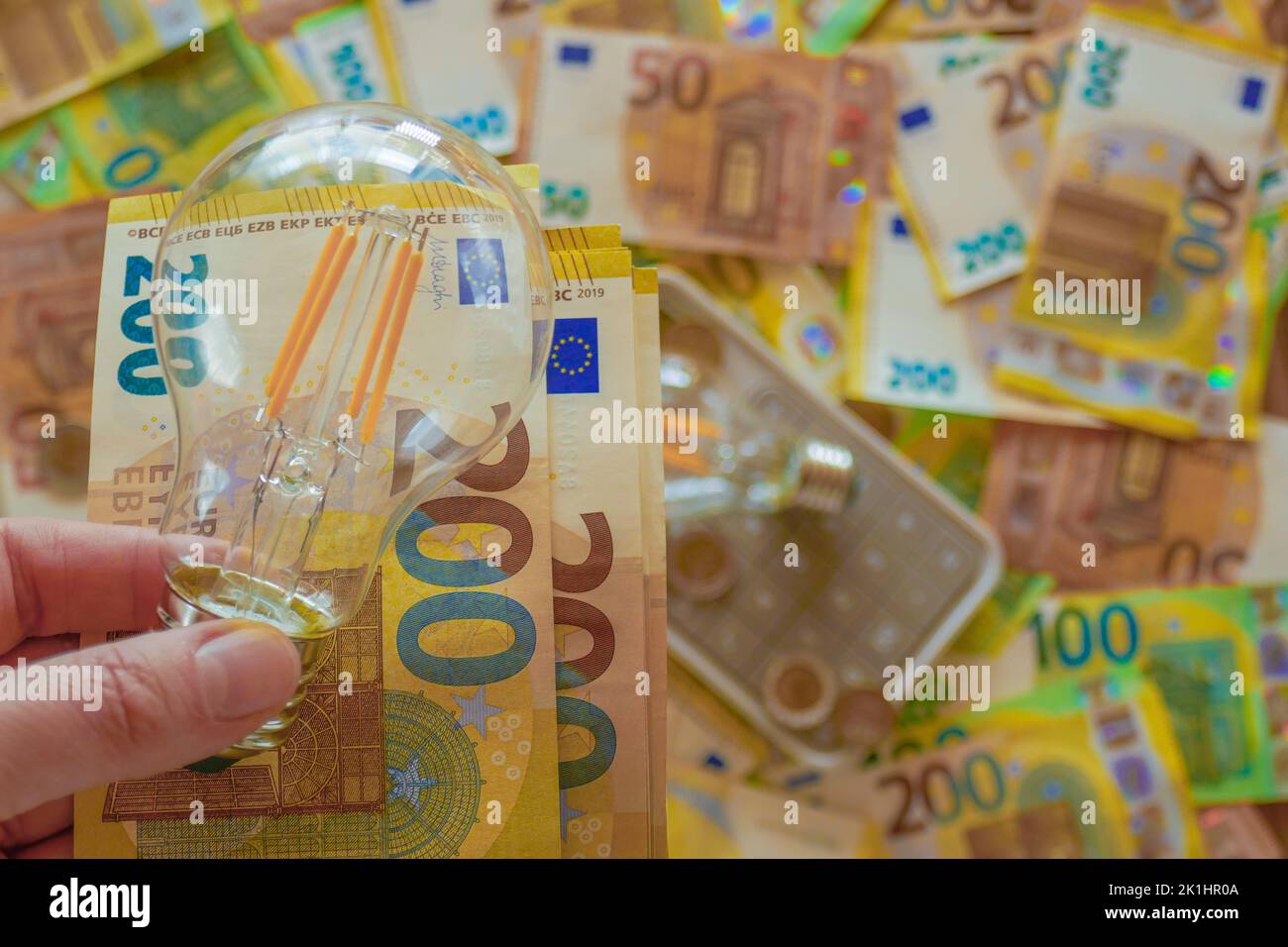 Electricity cost in Europe.Electric light bulb in hand on euro bills ...
