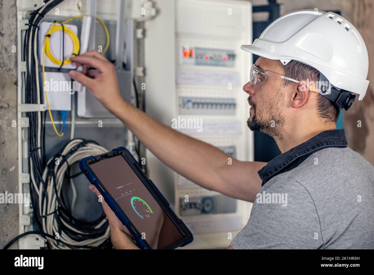 Man, an electrical technician working in a switchboard with fuses, uses a tablet Stock Photo - Alamy
