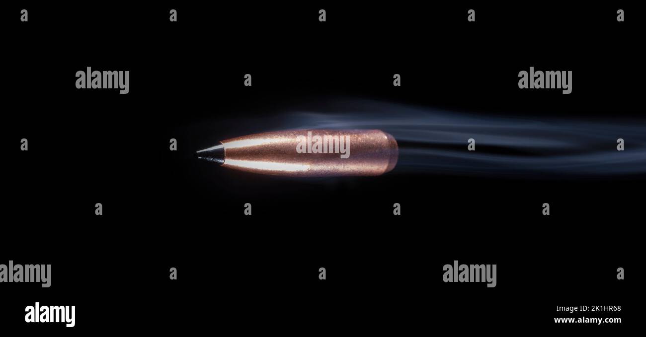 Copper plated bullet on a black background with white smoke trailing ...