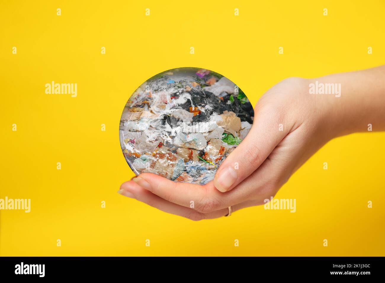 Defocus female hand holding trash planet over yellow background. Save ...