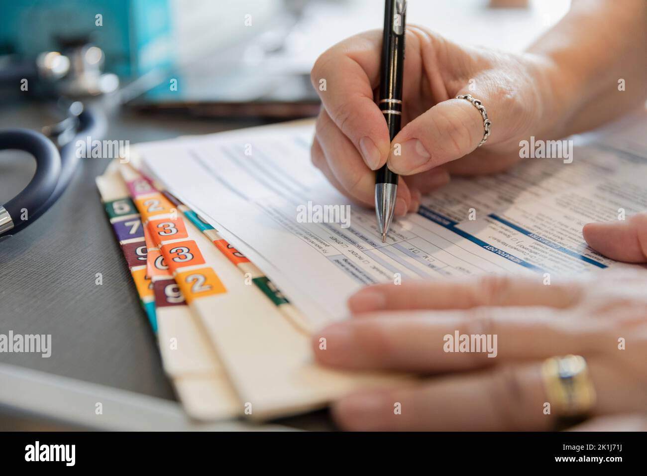 Doctor checking paperwork in consultation room Stock Photo - Alamy