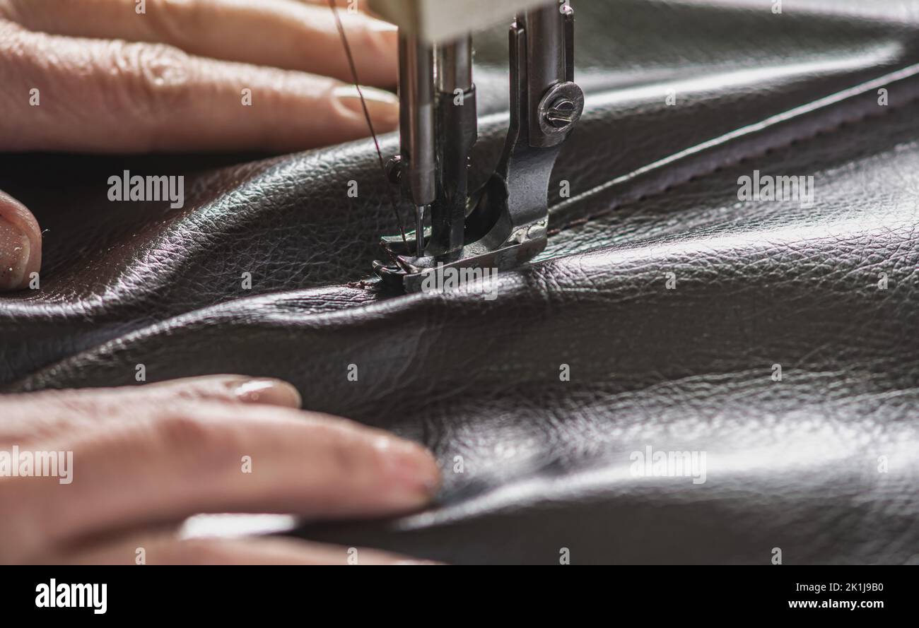 Women's hands in the process of sewing on professional equipment ...