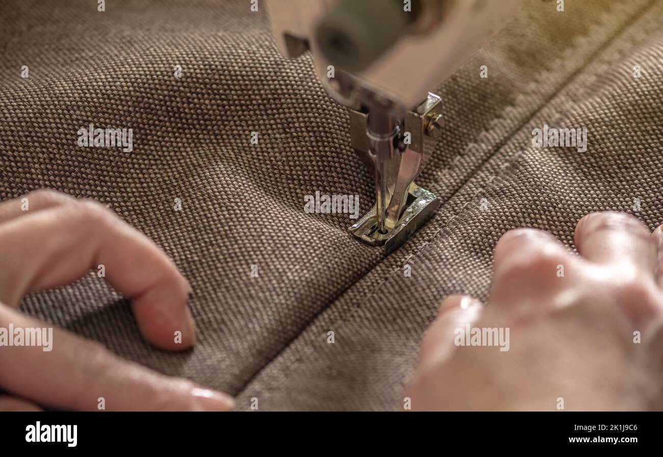 Women's hands in the process of sewing on professional equipment ...