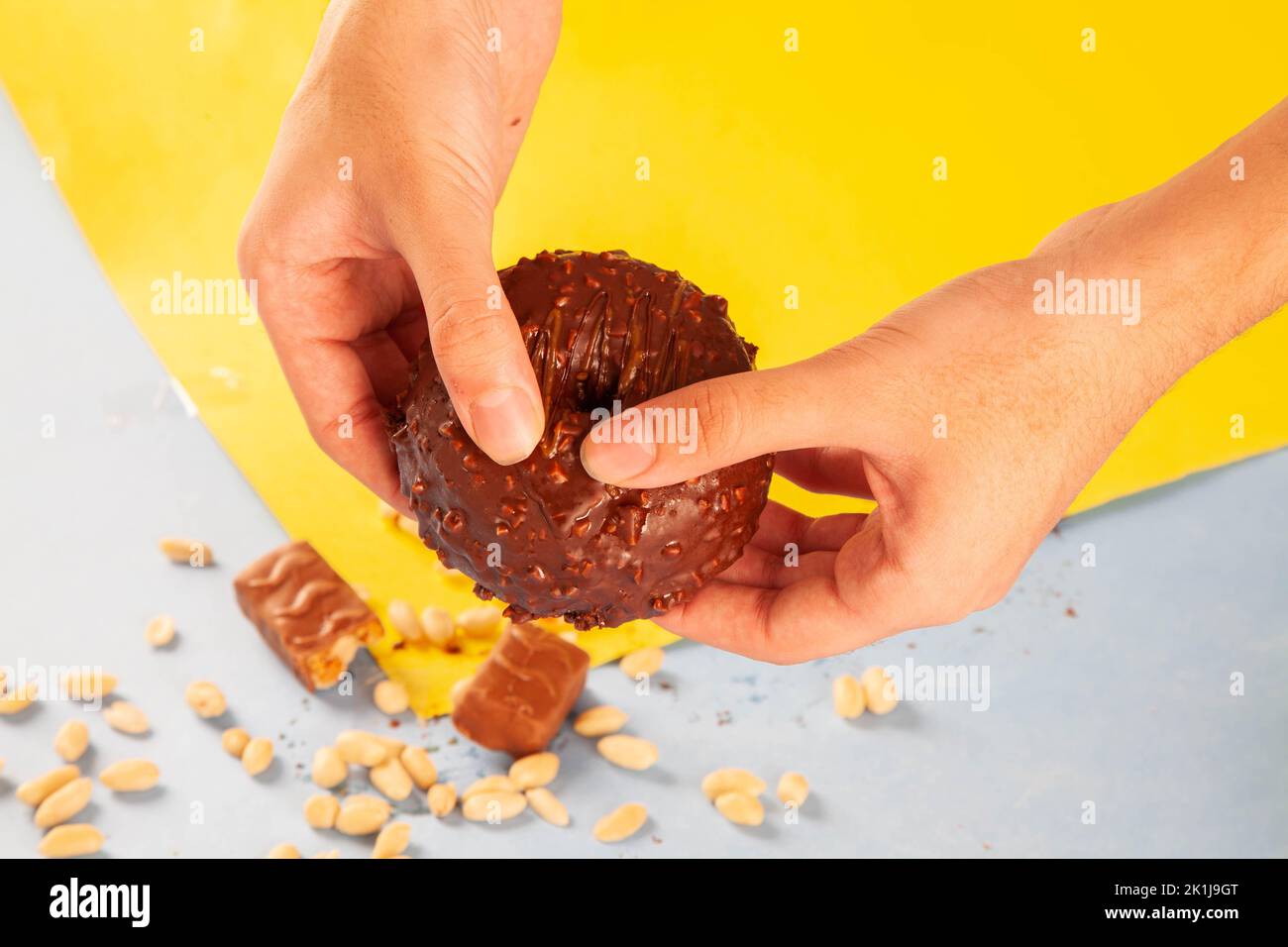 Hand splitting a chocolate crunchy nutty doughnut wide open Stock Photo ...