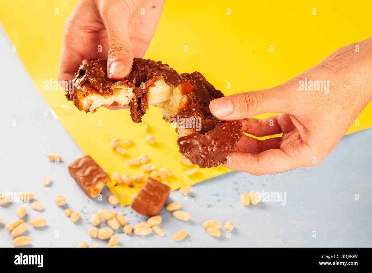 Hand splitting a chocolate crunchy nutty doughnut wide open Stock Photo ...