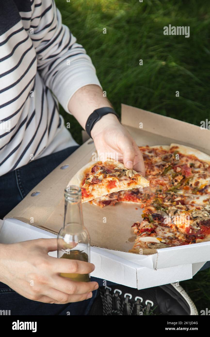 A young man eating pizza on a picnic Stock Photo - Alamy