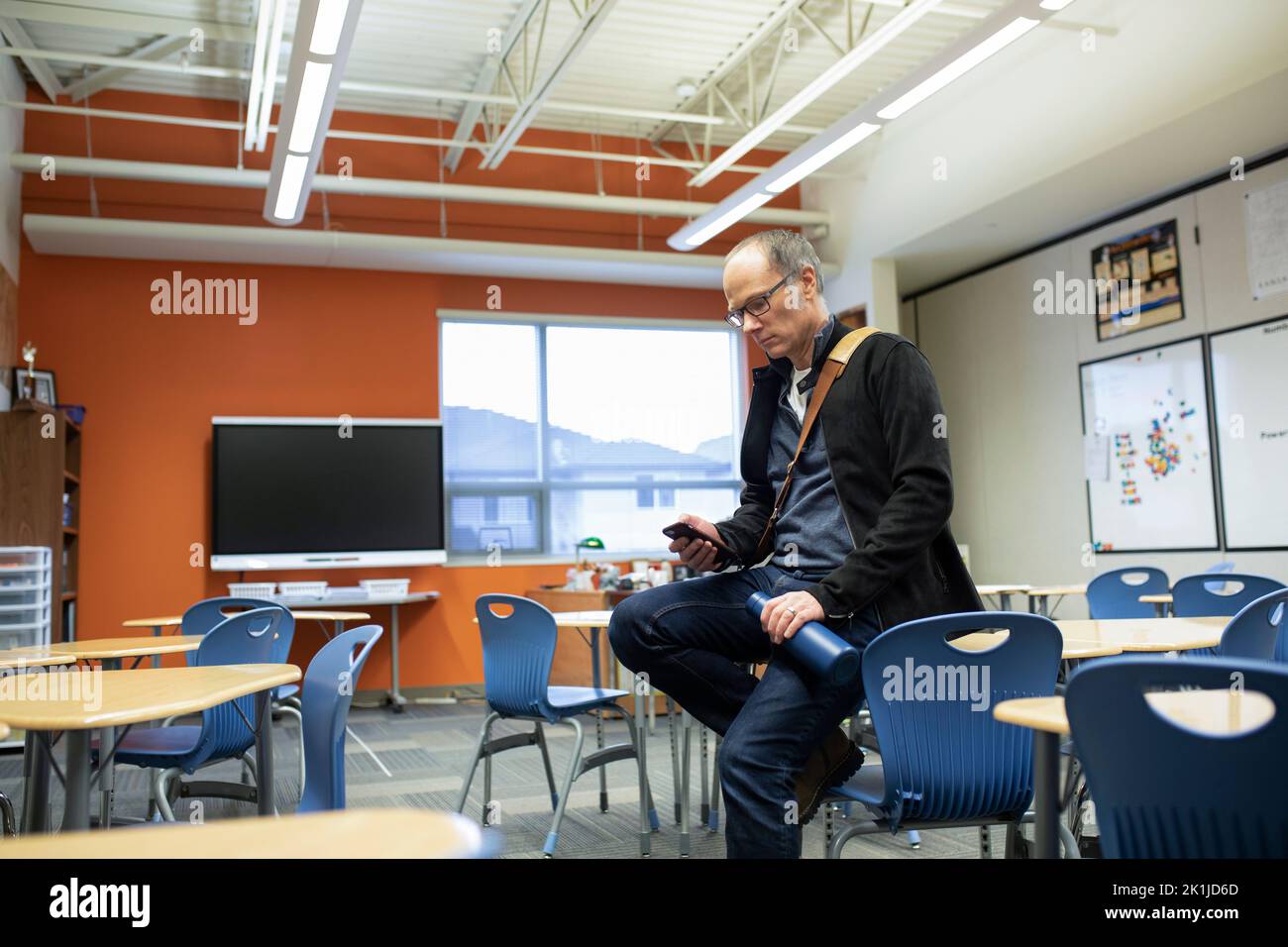 Male junior high teacher using smart phone in classroom Stock Photo - Alamy