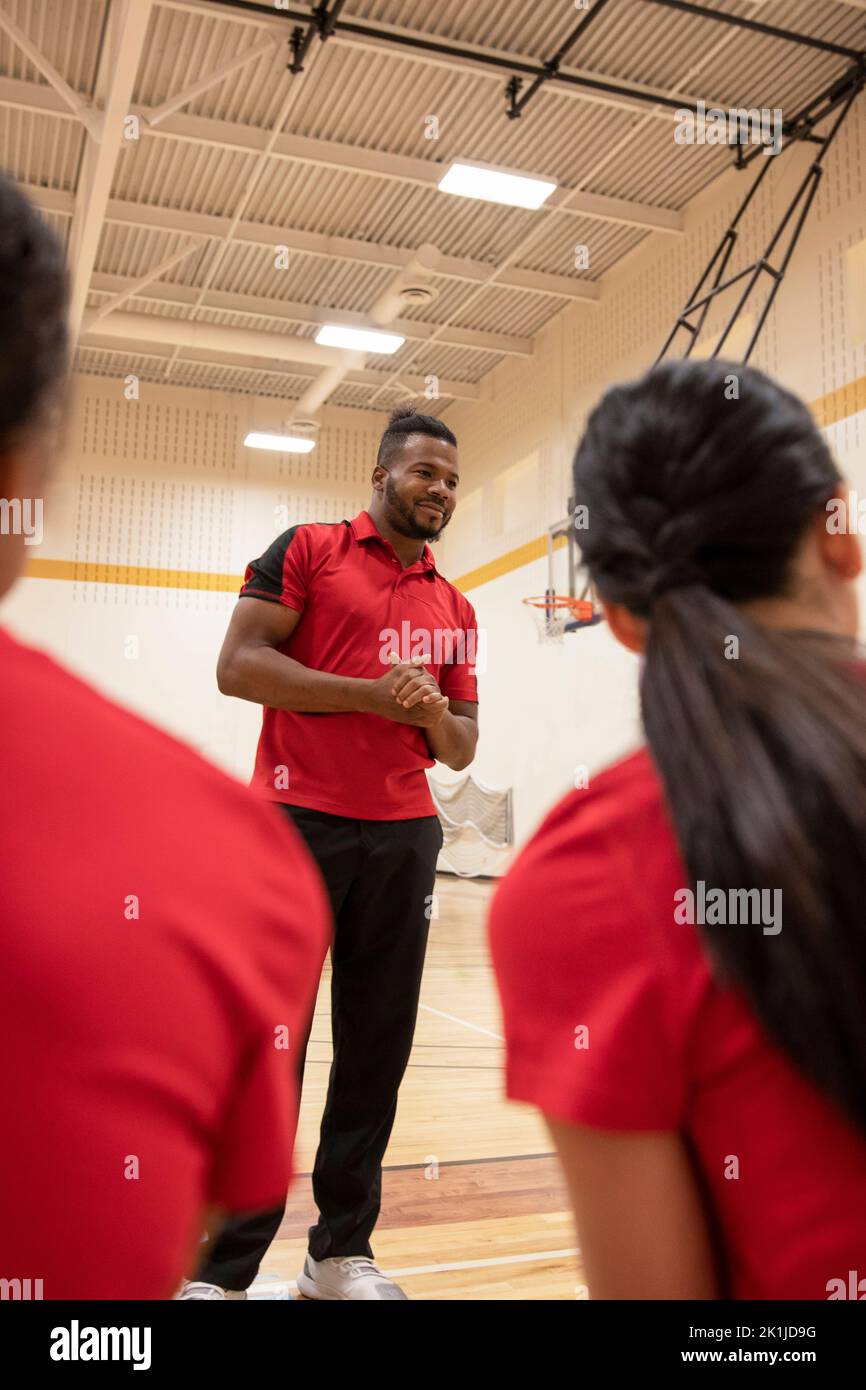 Male junior high basketball coach talking to team in gymnasium Stock ...