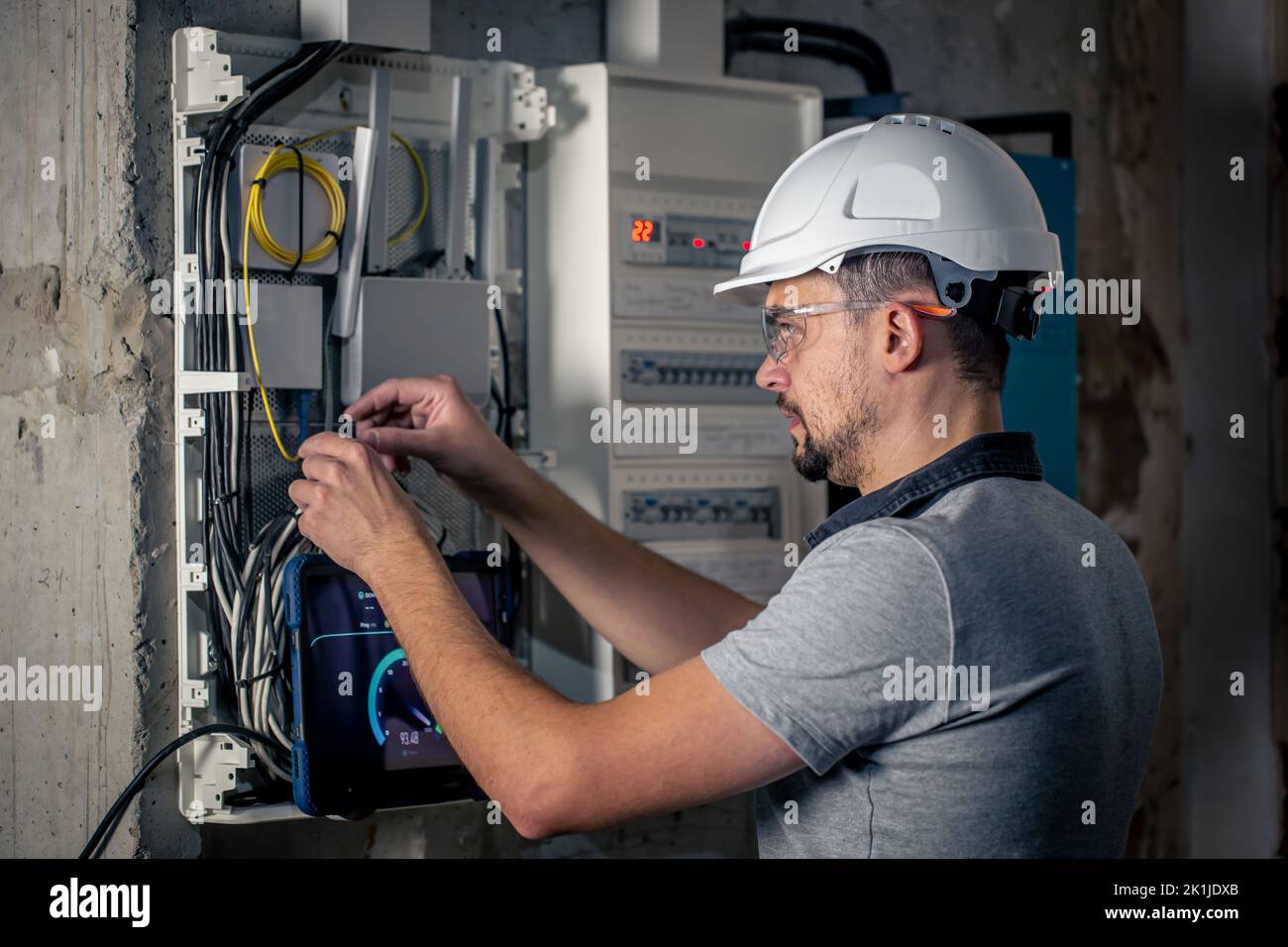 Man, an electrical technician working in a switchboard with fuses, uses ...