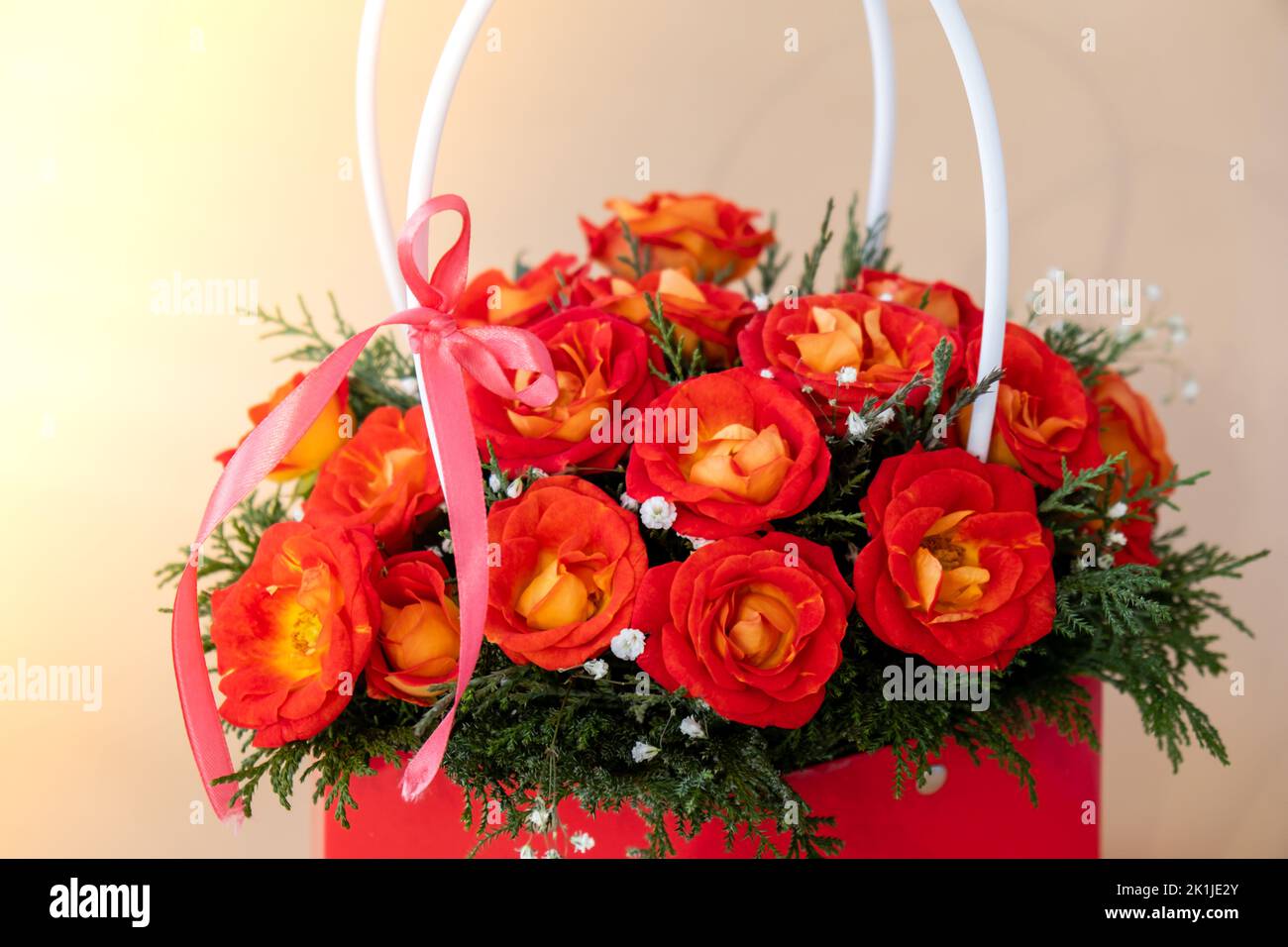 Bouquet of red roses decorated in hat box on light background. Tied bow ...