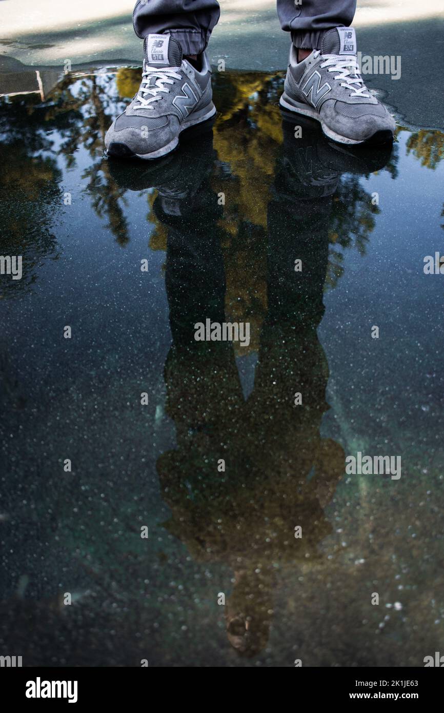 A Reflection of male gray boots in Puddle Water Stock Photo - Alamy
