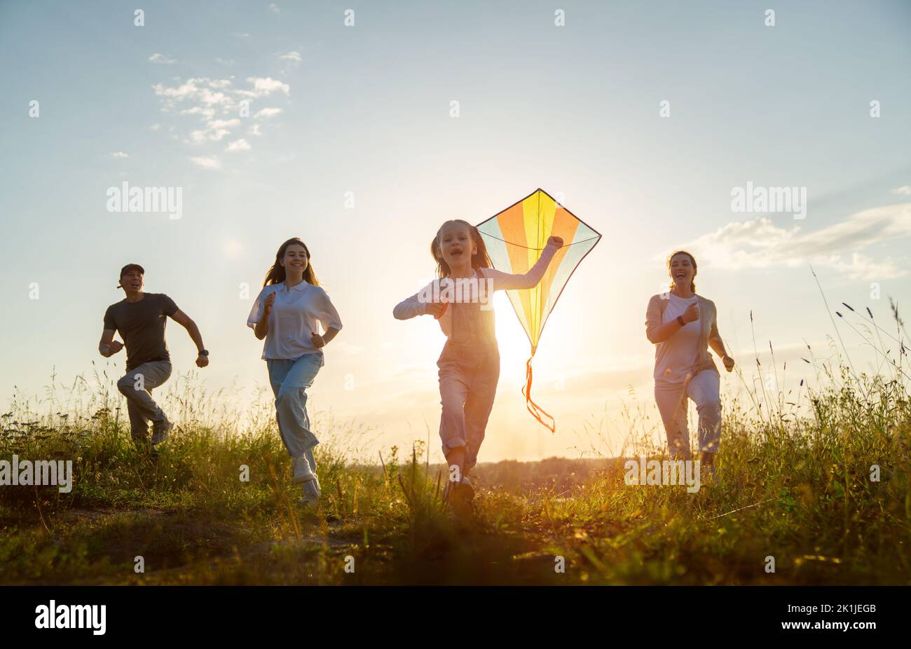 Happy family running through field with kite Stock Photo - Alamy
