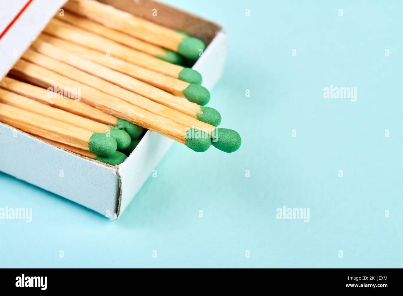 Many matches with green heads in a matchbox on a blue background with ...