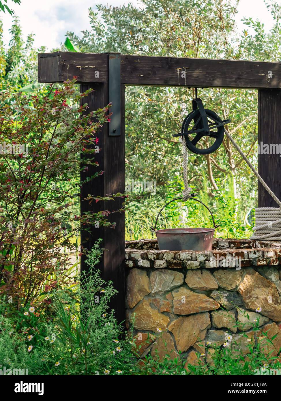 Beautiful artesian well made by stones and wheel pulley with metal ...