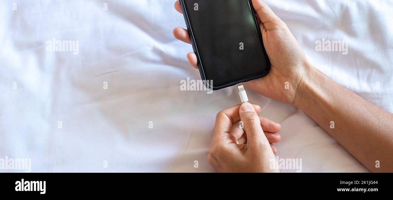 Woman hands charging battery in mobile smart phone in the bedroom at ...