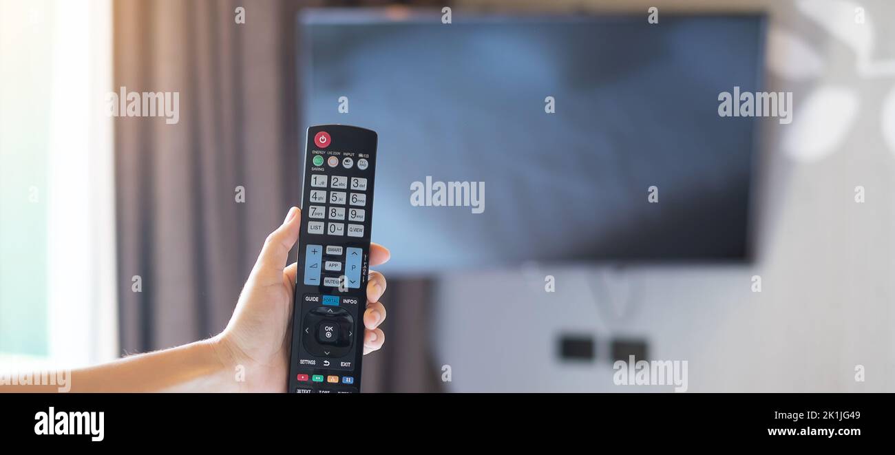 hand using remote controller for adjust Smart TV inside the modern room ...