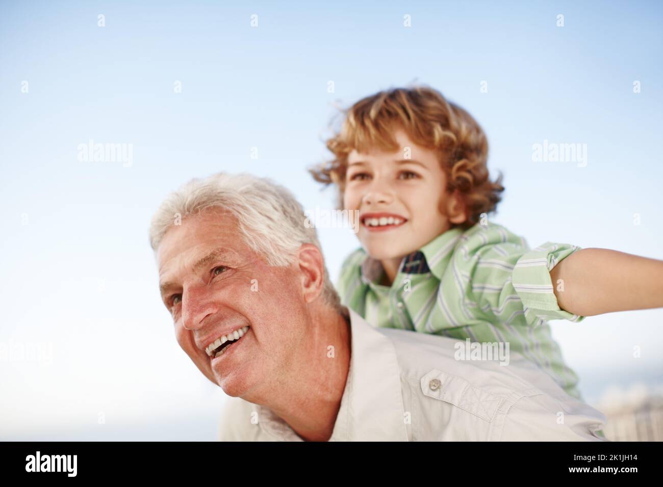 Riding high on grandpas back. a young boy getting piggybacked by his ...