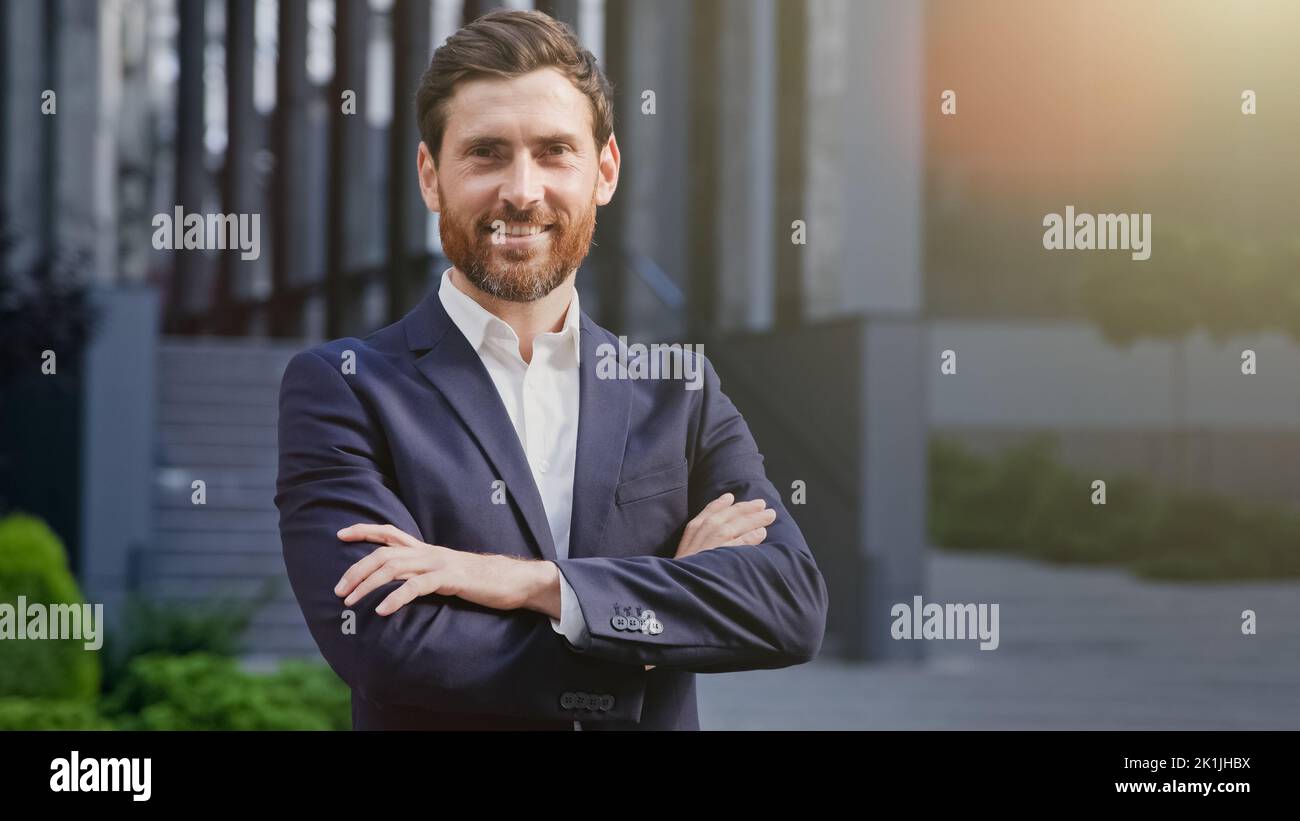 Successful confident smiling businessman in suit stands outdoors on ...