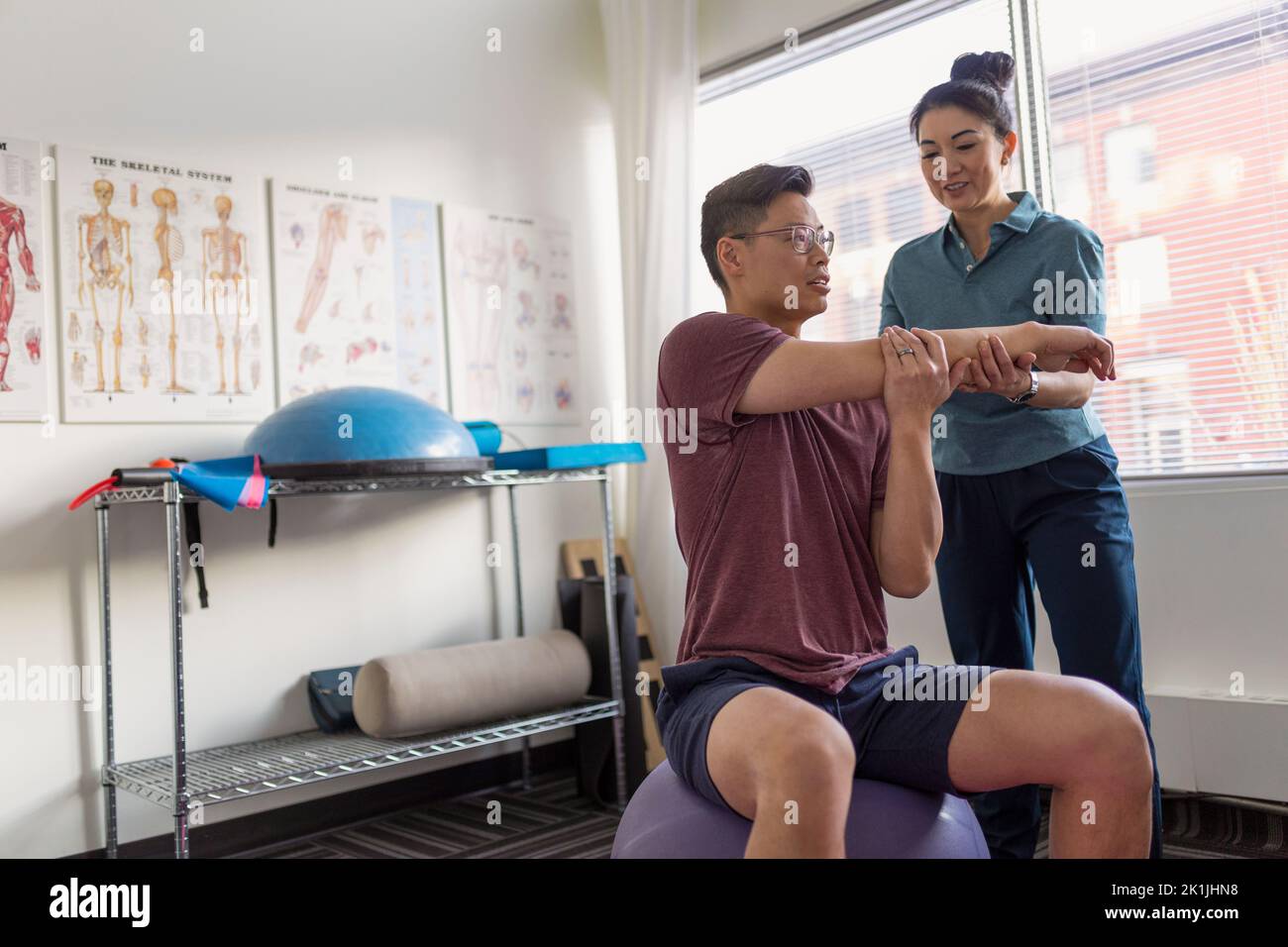 Physiotherapist helping male client with balance and stretching ...