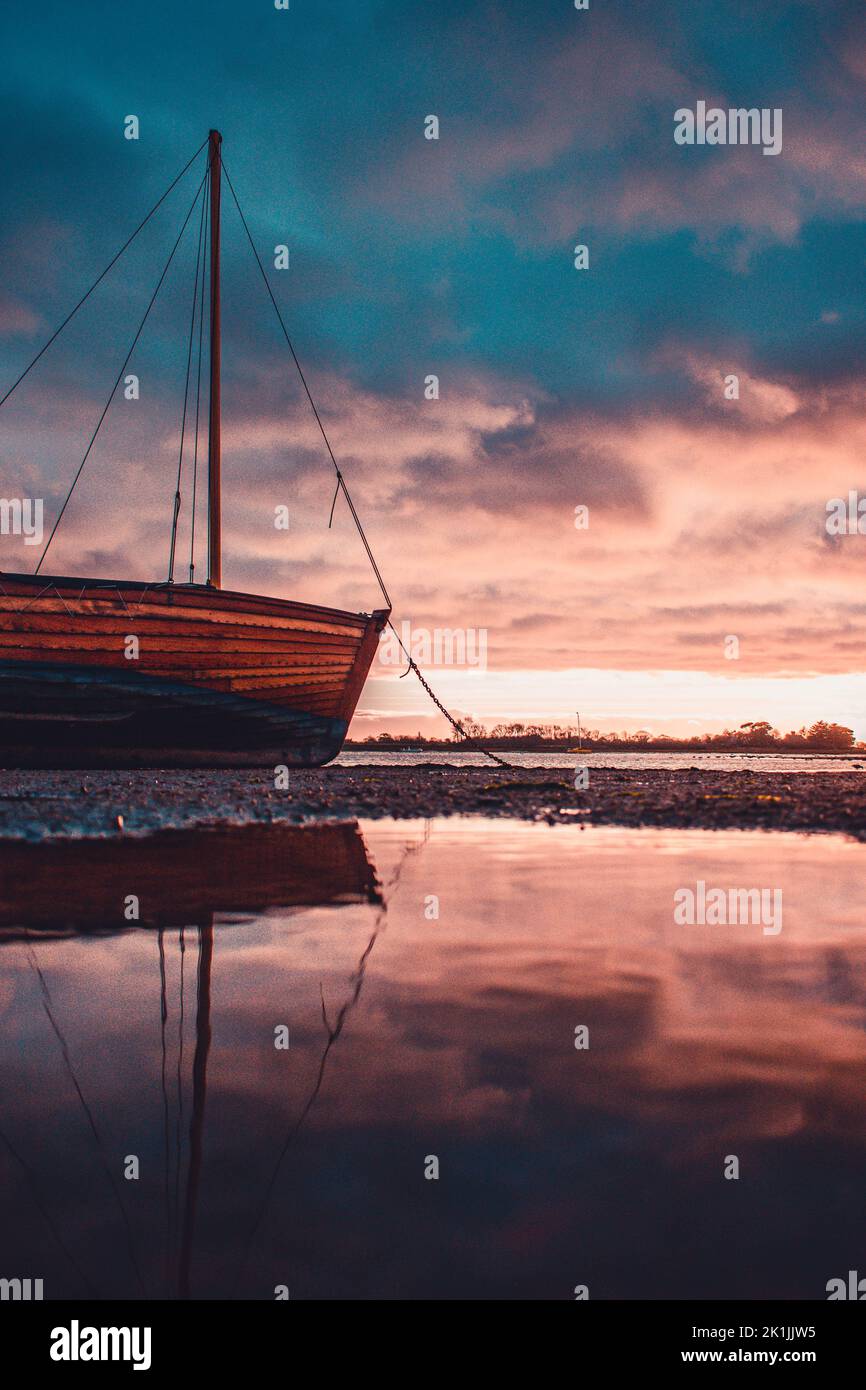 A vertical shot of a purple shade sunset over the sailing boat with a reflection on a water ...