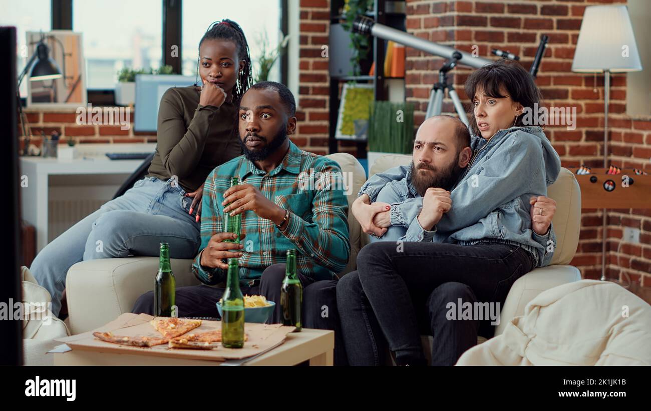 Diverse friends being scared watching horror movie, doing jump scare ...