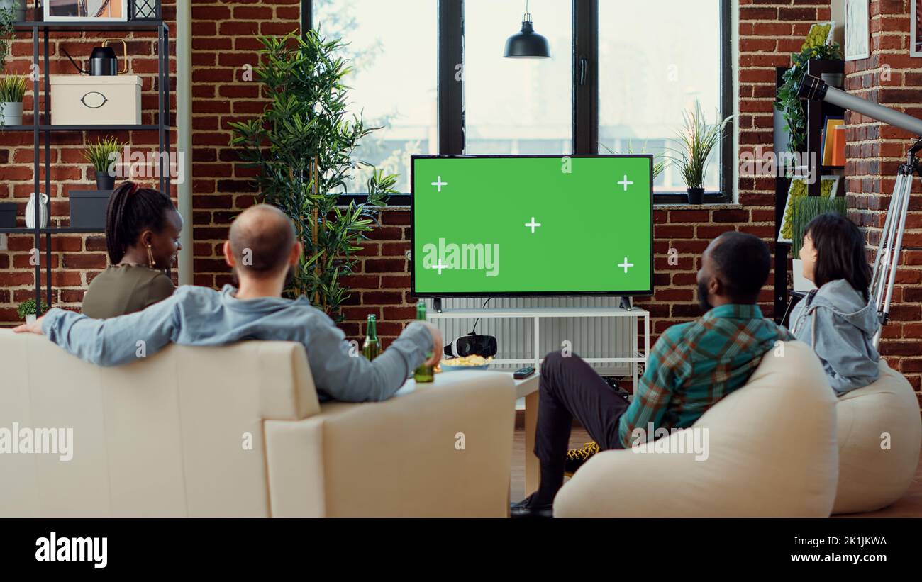 Group of people enjoying movie on television with greenscreen template ...