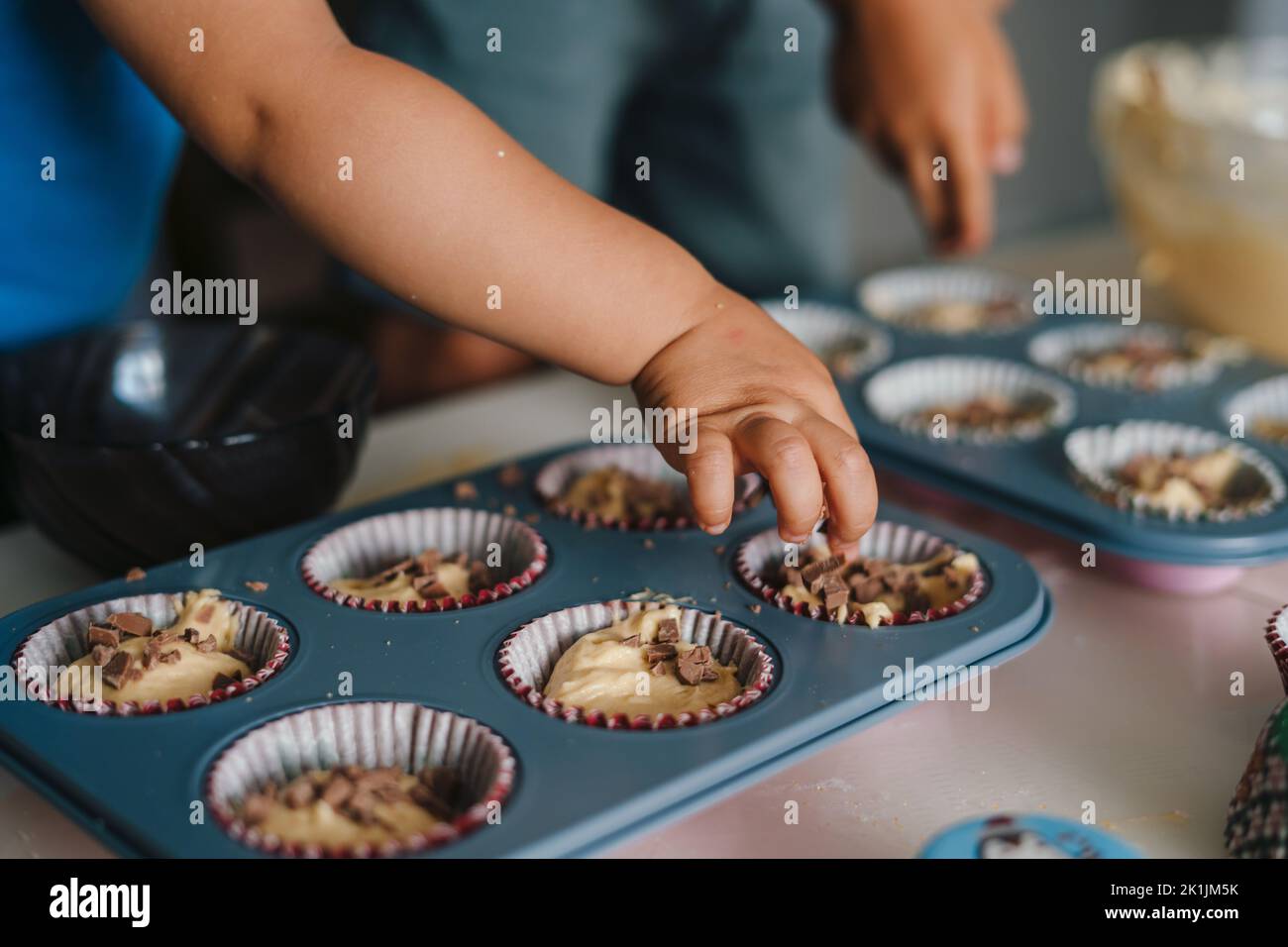 Cute girl's hands putting chocolate chips on the raw muffin batter in ...